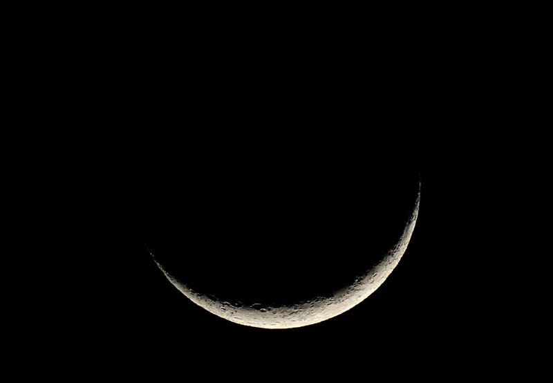 A crescent moon is seen during a conjunction with the planets Jupiter ...